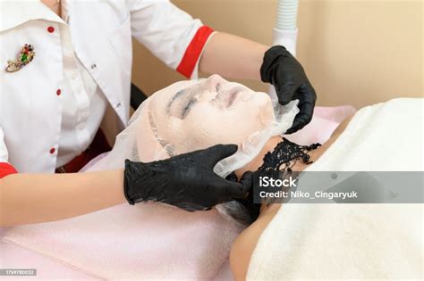 미용사는 손으로 환자의 얼굴에서 크림으로 거즈를 제거합니다 2명에 대한 스톡 사진 및 기타 이미지 2명 각질제거 거즈