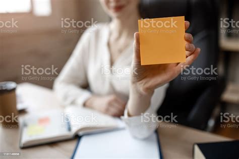 좋은 젊은 사업가 손에 노란색 스티커를 개최 합니다 그녀는 카메라를 보여줍니다 모델은 방에 앉아 있다 일광 가정의 방에 대한