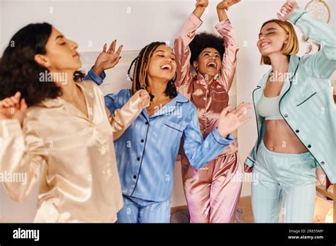 Excited And Cheerful Multiethnic Girlfriends In Colorful Pajama Dancing