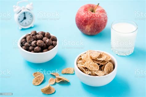시리얼과 초콜릿 볼 우유 한 잔 사과 파란 배경에 알람 시계가 있는 그릇 예정된 아침 식사 0명에 대한 스톡 사진 및 기타