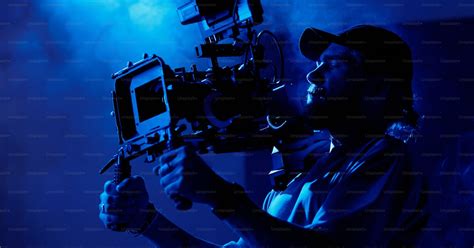 어두운 방이나 짙은 푸른 빛으로 비추는 연기로 가득 찬 스튜디오에서 상업 비디오를 촬영하는 캐주얼웨어를 입은 젊은 비디오그래퍼 사진 Unsplash의 푸른 연기 이미지