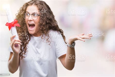격리 된 배경 매우 행복 하 고 흥분 상자 식 큰 웃음 소리는 승리를 축 하 하 고 손을 통해 안경 착용 하 고 학위를 들고 젊은 갈색 머리 여자 갈색 머리에 대한 스톡