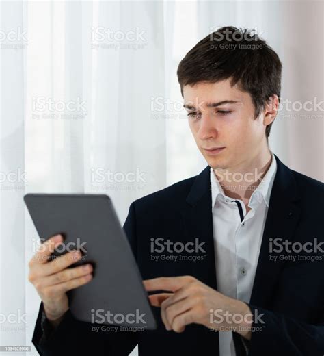 태블릿으로 진지하게 일하는 백인 사업가를 닫고 정장을 입고 서서 태블릿을보고 젊은 남자는 홈 오피스 배경과 복사 공간을 가진