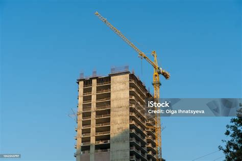 노란색 건설 크레인의 클로즈업과 푸른 하늘 배경에 건설 중인 다층 건물의 일부 0명에 대한 스톡 사진 및 기타 이미지 0명