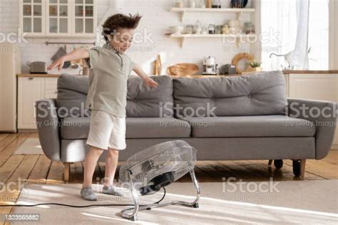 어린 소년은 거실에서 팬의 공기 흐름을 즐길 수 있습니다 귀여운 작은 아이 놀이 와 인공 호흡기 불어 바람 신선함에 대한 스톡 사진 및 기타 이미지 Istock