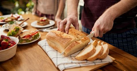 집에서 아침 식사를 하는 동안 빵 한 덩어리를 자르는 남자의 클로즈업 사진 Unsplash의 빵 이미지
