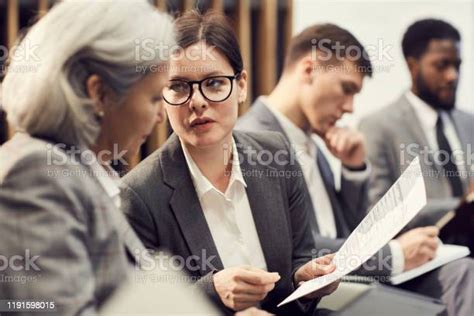 강당에 앉아 서 서 신청서에 대 한 동료와 이야기 하는 안경에 매력적인 젊은 사업가 경영자에 대한 스톡 사진 및 기타 이미지