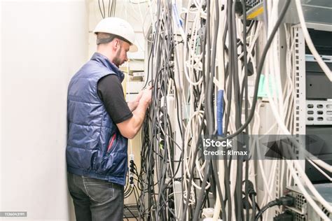 기술자는 데이터 센터에서 많은 전선으로 작업 합니다 흰색 헬멧에 있는 엔지니어는 서버 룸의 랙에 전기 통신 전선을 연결 합니다