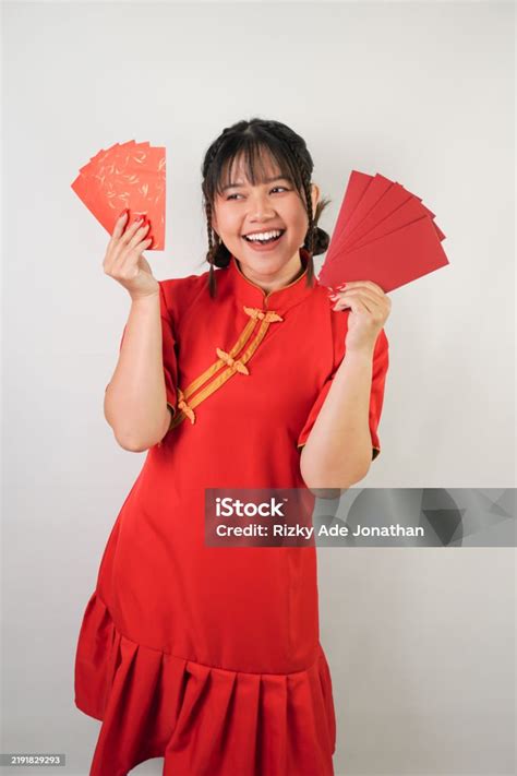 빨간 전통 중국 드레스를 입고 웃는 젊은 아시아 여성은 흰색 배경 위에 고립 된 많은 빨간 봉투를 들고 있습니다 음력 설날 파티에 대 한 개념 12월 31일에 대한 스톡