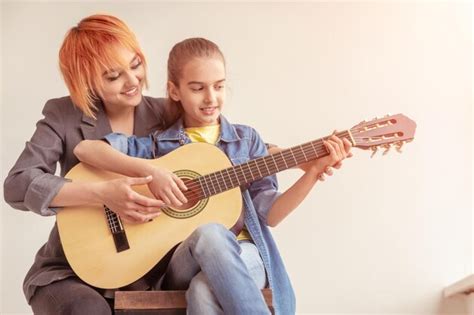 Mulher ensinando menina a tocar violão Foto Premium