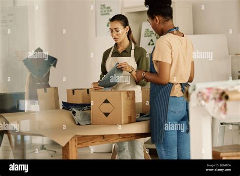 Two Colleagues Unpacking Boxes Fashion Designers Packing Stock Order