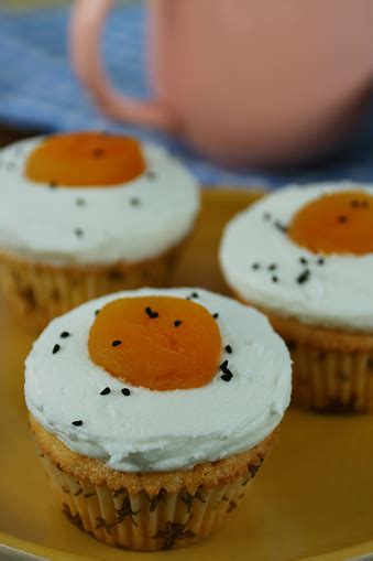 홈메이드 튀긴 달걀 바닐라 컵케이크의 클로즈업 이미지 흰색 파이프 착빙 프로스팅과 말린 살구를 종이 케이크 케이스에 얹고 구운 통밀 빵 삼각형 조각 배경에 분홍색 우유