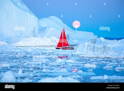 Little Red Sailboat Cruising Among Floating Icebergs In Disko Bay