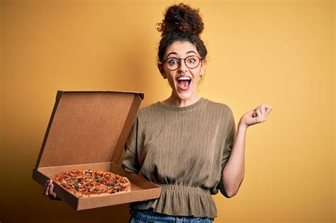 곱슬 머리와 피어싱 배달 상자를 들고 이탈리아 피자 자랑과 승리와 성공을 축하 매우 흥분 응원 감정을 가진 젊은 아름다운 여자