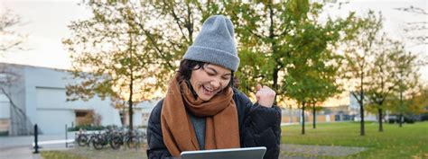 Portrait Of Happy Asian Girl Sits On Bench Looks At Digital Tablet