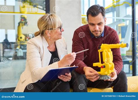 Engineers Discussing Robotic Gripper Arm Development In A Modern Industrial Setting Stock Image