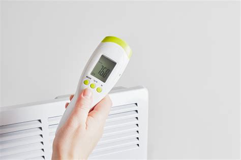 전기 라디에이터의 배경에 표면 온도와 공기를 측정하기위한 전기 적외선 온도계 가정의 방에 대한 스톡 사진 및 기타 이미지
