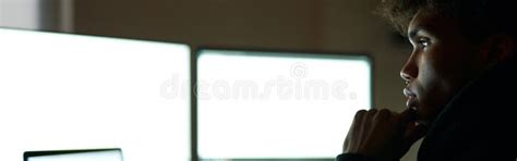 Work All Night Focused Young Guy Sitting In Dark Room In Front Of Many Computer Monitors While
