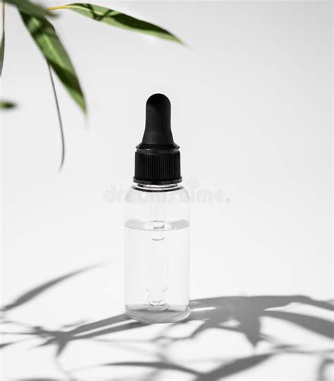 Body And Face Massage Oil On A White Background With Green Leaves And
