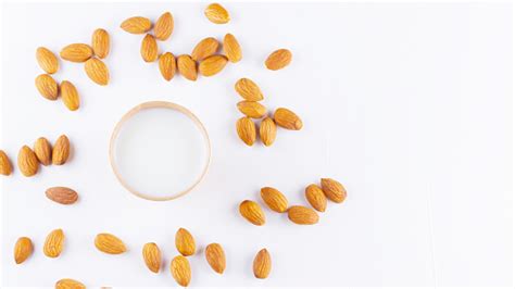 흰색 배경에 아몬드와 아몬드 우유 건강한 아침 식사를 위해 종이 컵에 수제 유기농 아몬드 우유 크래프트 종이 컵에 아몬드 견과류에서 비건 우유 대체 우유 폐기물 제로 0명에