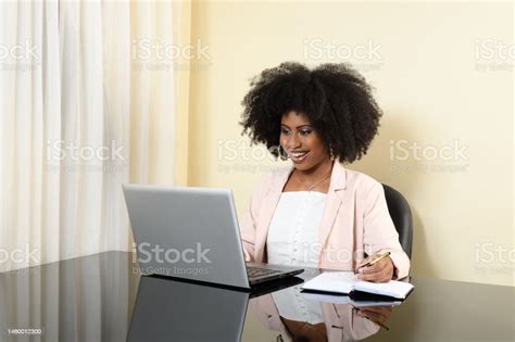 Young Woman Sitting At Her Desk Typing On Her Laptop Camputer Keyboard
