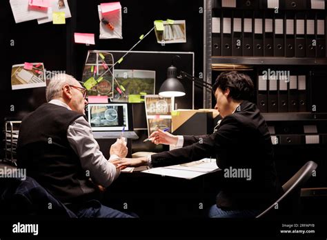 Old Investigator Analyzing Federal Documents With Inspector Discussing Crime Scene Evidence In