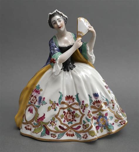 A Porcelain Figurine Is Holding A Fan