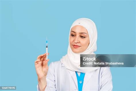 청진기와 주사기를 손에 들고 하얀 코트를 입은 친절한 무슬림 의사 또는 간호사 여성의 초상화 파란색 배경에 의학 및 의료 25 29세에 대한 스톡 사진 및 기타 이미지