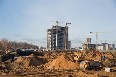 건설 크레인과 건물의 배경에 건설 현장에서 굴삭기 백호는 기초의 땅을 파고 폭풍 하수 파이프를 누워 물 주요 시스템의 설치 건설