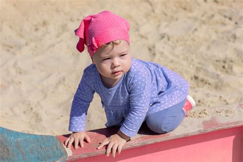 파란 드레스를 입은 어린 소녀는 샌드 박스 의 가장자리에있는 모든 네 발위에 서 있으며 여름 화창한 날 산책 수평 구성에 대한 스톡 사진 및 기타 이미지 Istock