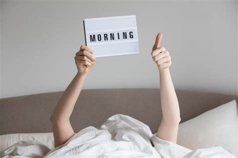 Premium Photo Female In Bed Under The Sheets Holding Up A Morning Sign
