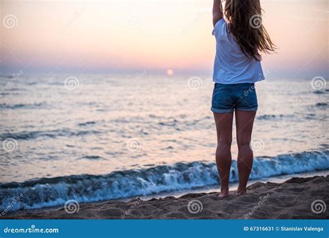 Jovem Mulher Que Está Na Pedra Olhando O Por Do Sol Sobre O Mar Imagem