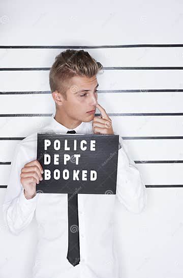 Caught In The Act Mug Shot Of A Young Man In A Shirt And Tie Holding