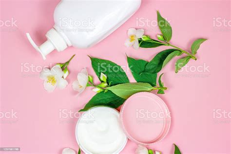 분홍색 배경에 밝은 신선한 재스민 꽃을 모방한 모의로 보습 크림을 위한 흰색 플라스틱 화장품 용기의 최고 전망 바디 와 스킨