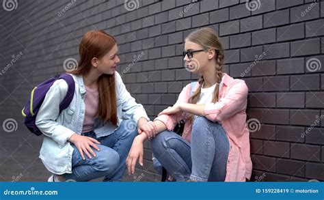 Caring Female Teenager Supporting Lonely Classmate Sitting Aside