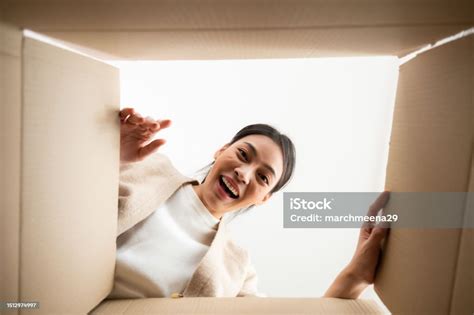 놀란 젊은 아시아 여성이 포장을 풀고 있다 판지 상자를 열고 내부를 들여다봅니다 포장 상자 배달 서비스 인간의 감정과 표정 개념에 대한 스톡 사진 및 기타 이미지 Istock