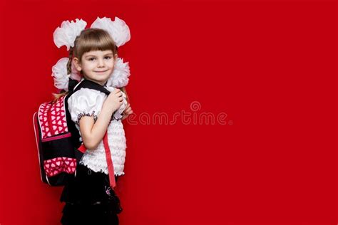 Милая маленькая девочка Smilng в школьной форме и белизне обхватывает с