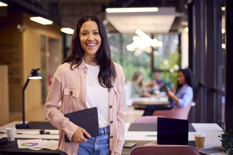 Portrait Of Smiling Businesswoman Standing In Modern Open Plan Office