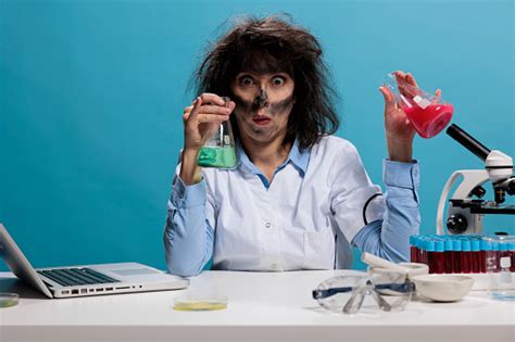 미친 바보 같은 미친 실험실 직원이 실험용 액체 화합물로 채워진 유리 병을 가지고 책상에 앉아 있습니다 Dna에 대한 스톡 사진