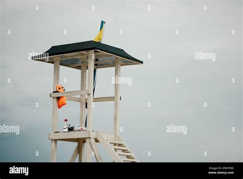 Empty White Lifeguard Tower With A Yellow Flag On The Beach In Windy
