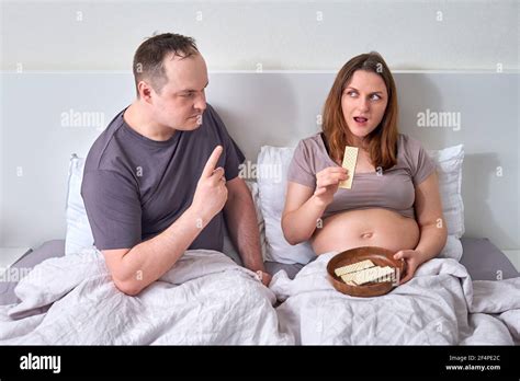 A Man Forbids A Pregnant Woman To Eat Junk Food From A Plate Of Sweets