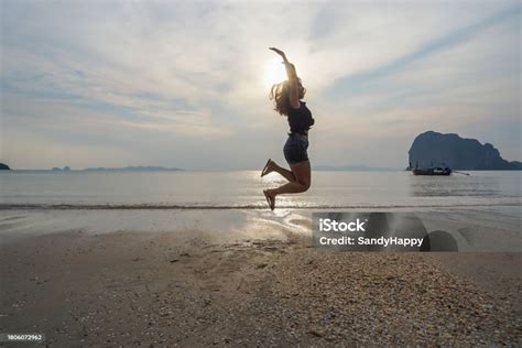 새벽 시간에 해변에서 뛰어 오르는 행복 한 아시아 소녀 해변에서 기쁨의 점프하는 행복 한 여자 자유로운 몸으로 자유와 행복의