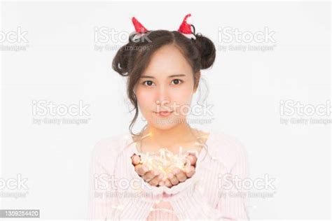 작은 산타 모자를 쓰고 흰색 배경에 크리스마스 조명을 들고 분홍색 스웨터를 입은 아름다운 아시아 여성 25 29세에 대한 스톡