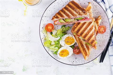 햄 토마토 치즈 아보카도 커피 한 잔을 곁들인 클럽 샌드위치 파니니구이 맛있는 아침 식사 또는 간식 상단 보기 플랫 레이 건강한