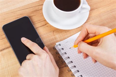 Hand Of Woman Using Mobile Phone Or Smartphone And Writing Notes In Notepad Stock Photo Image