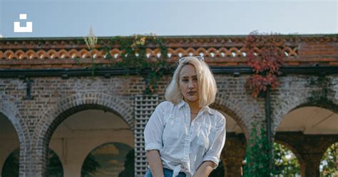 하얀 드레스 셔츠와 푸른 데님 청바지를 입은 여자가 낮 동안 푸른 잔디밭에 서 있다 사진 Unsplash의 무료 홀랜드 파크 이미지