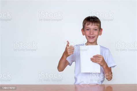 손에 흰색 노트북을 들고 있는 귀여운 백인 소년의 초상화가 엄지손가락을 들고 있었다 학교로 돌아가기 위한 컨셉 아이에 대한 스톡