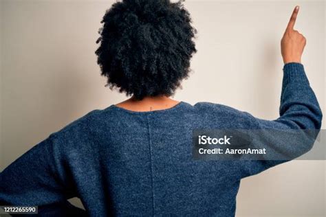 젊은 아름다운 아프리카계 미국인 Afro 여자 와 곱슬 머리 착용 캐주얼 스웨터 포즈 뒤로 가리키는 앞을 가리키는 손가락 손