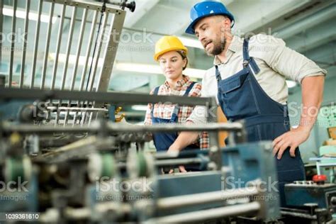 심각한 자신감 수염 Hardhat 공장에서 여성 인턴 과정을 설명 하 고 생산 기계를 보고에서 포먼 공장 산업 건물에 대한 스톡