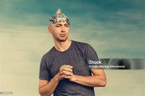 호일 모자를 쓴 남자가 의심스럽게 윙크하고 파란 배경을 바라본다 모자 모자류에 대한 스톡 사진 및 기타 이미지 모자 모자류 알루미늄 호일 Istock